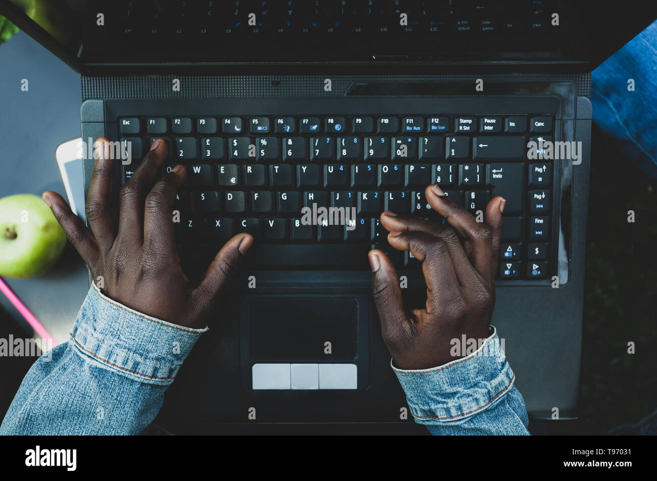 Close up hands of a young african woman typing on the laptop keyboard ...