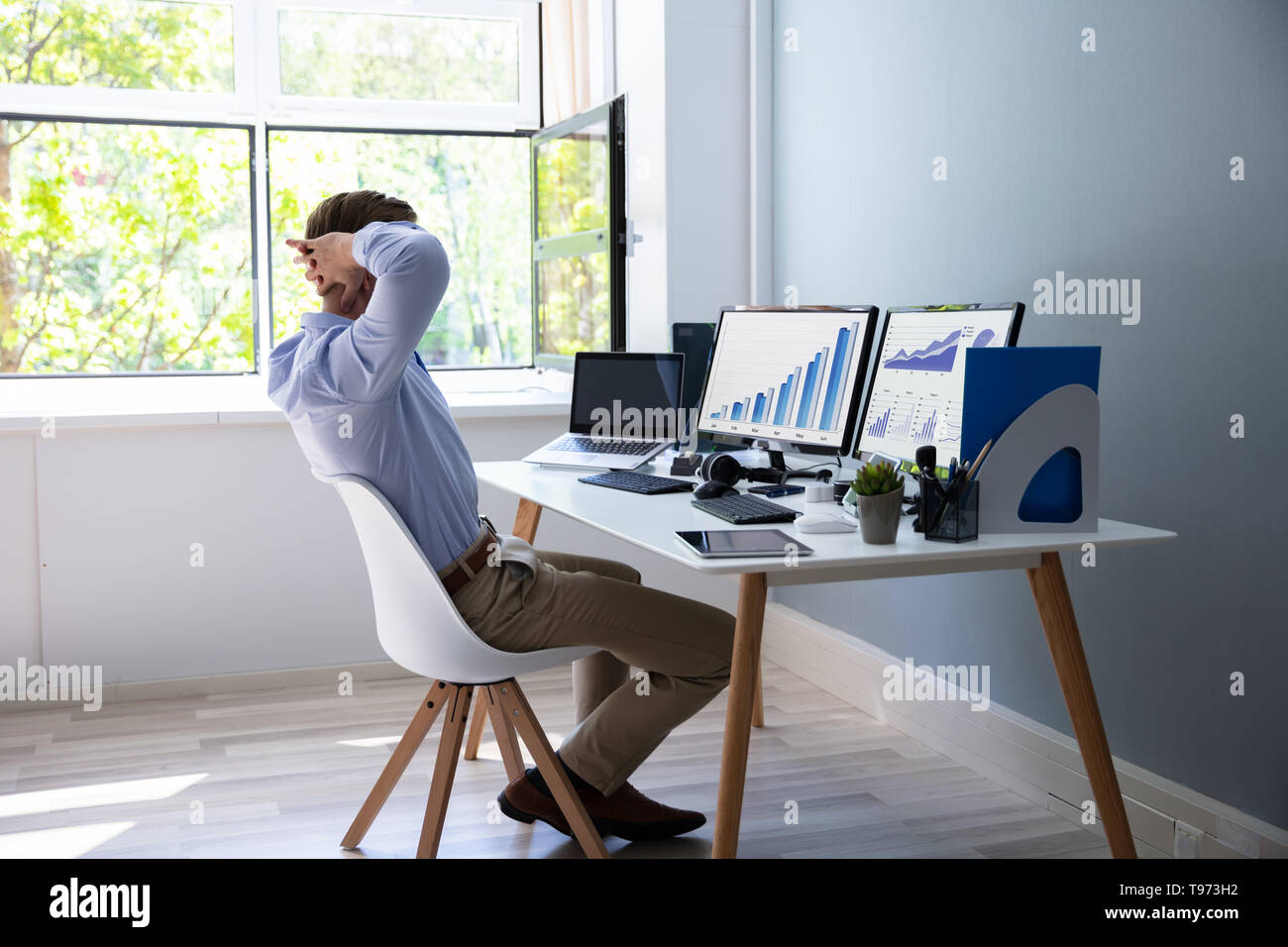 Relaxed Young Businessman Relaxing On Chair Behind Desk At Office Stock ...