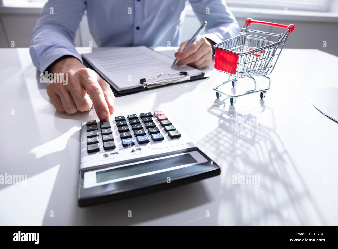 Close-up Of Man Calculating Shopping Expenses Near Shopping Trolley ...