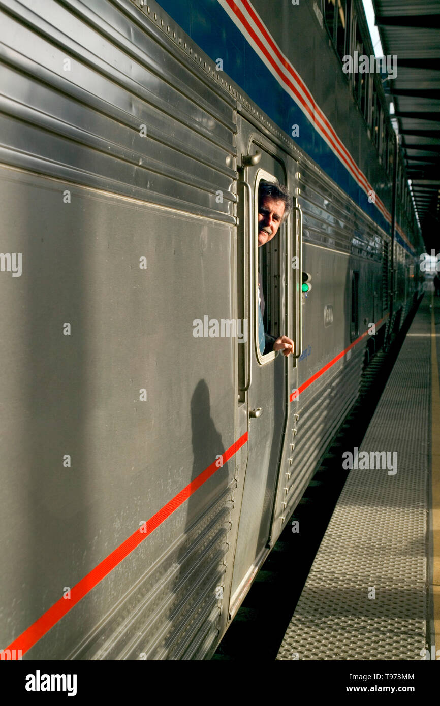 A passenger train conductor makes a final door check as the train ...