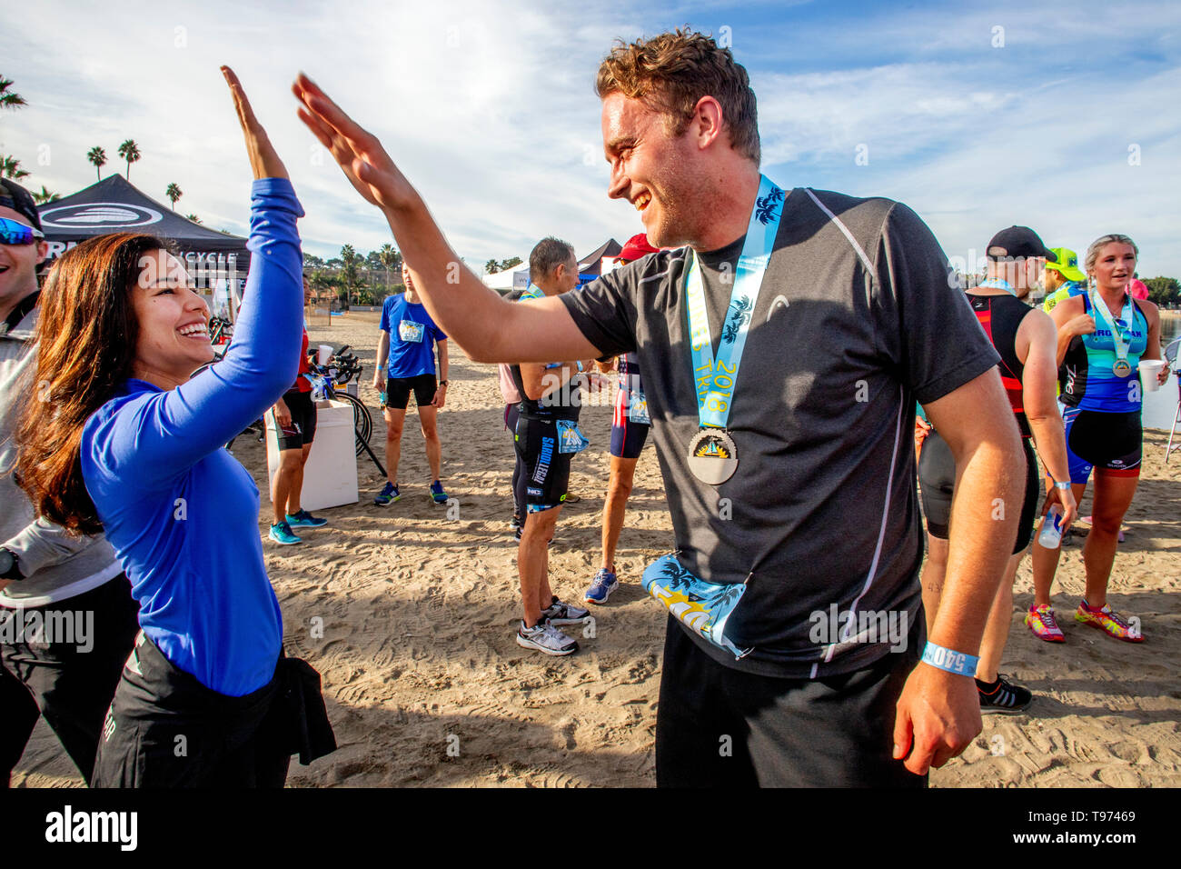 Wearing a finishing medallion, a triathlete gets high five ...