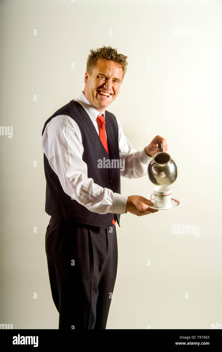 A uniformed passenger train waiter laughingly pours a cup of coffee at ...