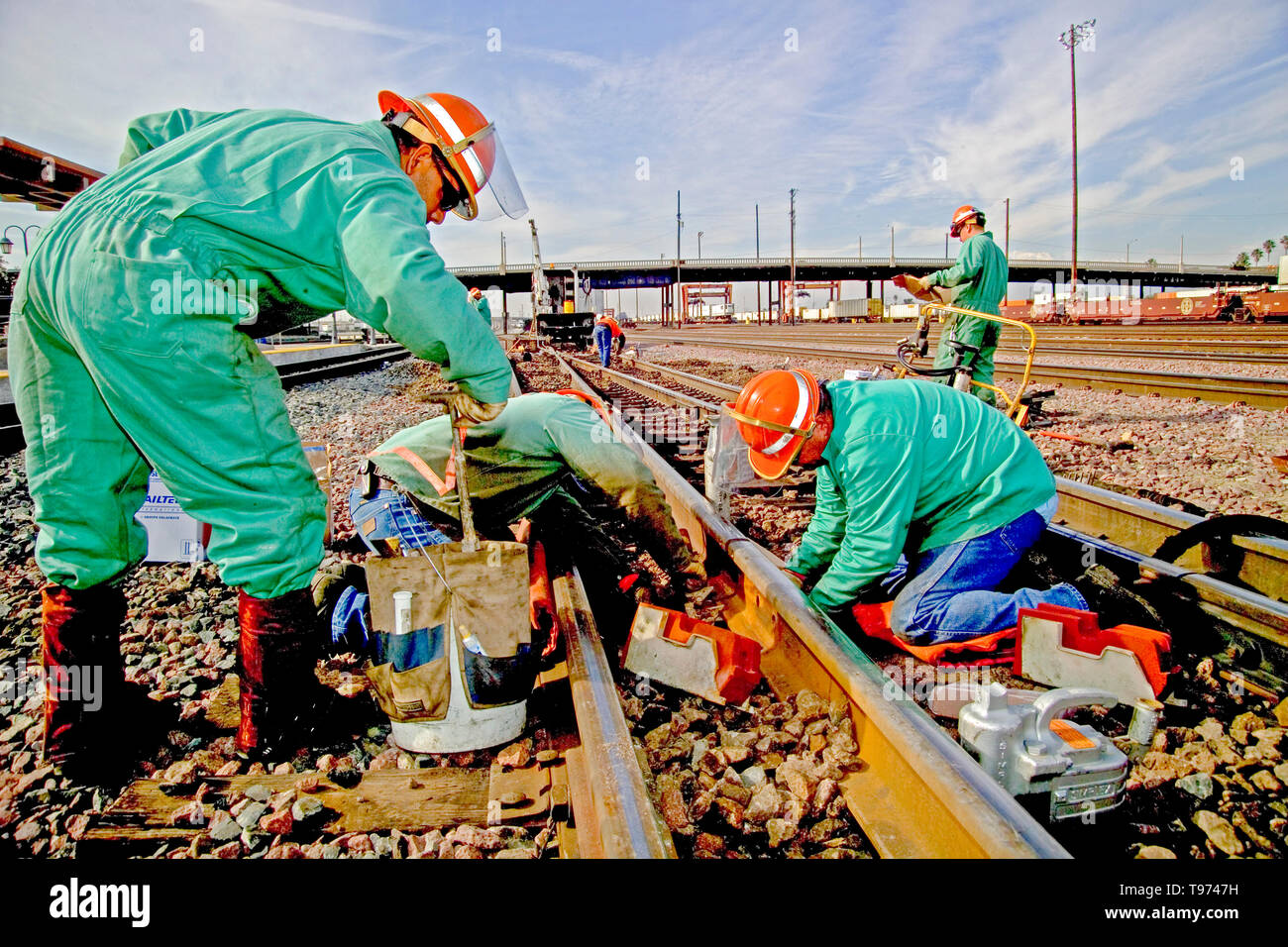 Three railroad maintenance workmen repair a track at a station in San ...