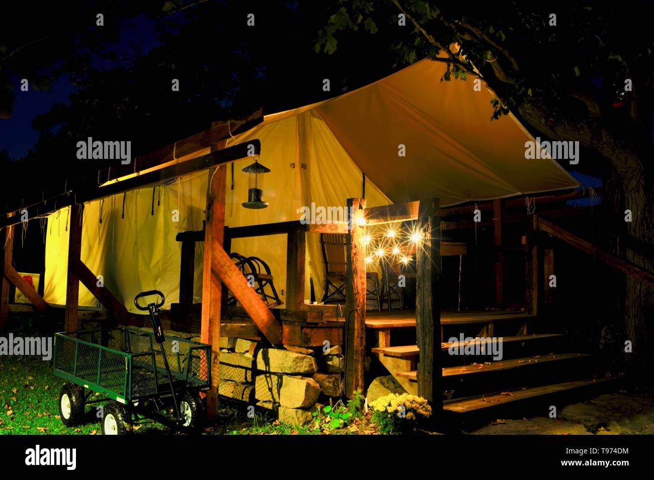 Exterior of canvas tent lit up at night, under the stars, for "glamping ...