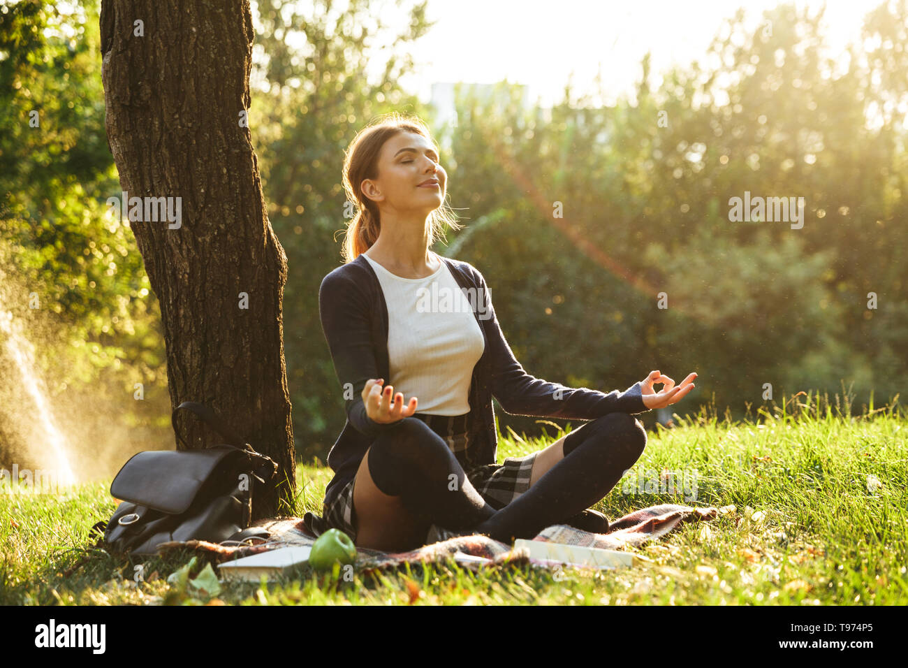 Cheerful teenage girl wearing uniform studying while relaxing at the ...