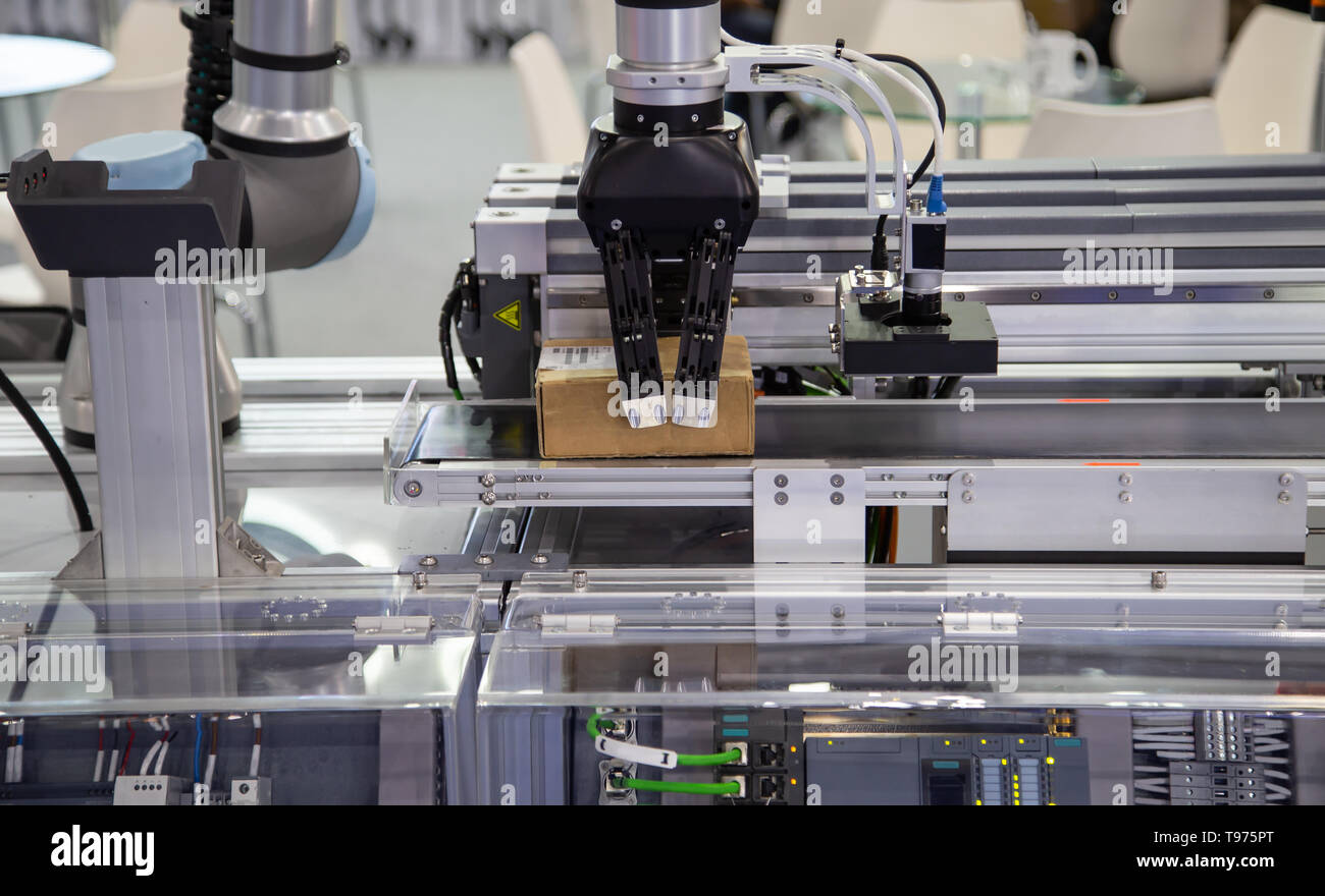 Robot arm loading carton on conveyor in manufacturing production line ...