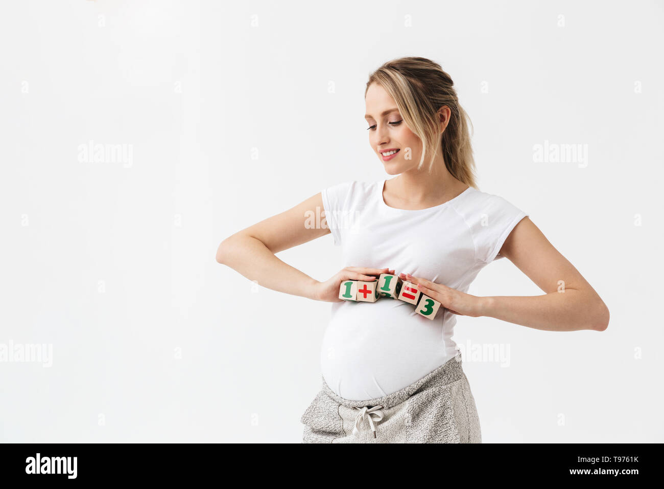 Beautiful young pregnant woman standing isolated over white background ...