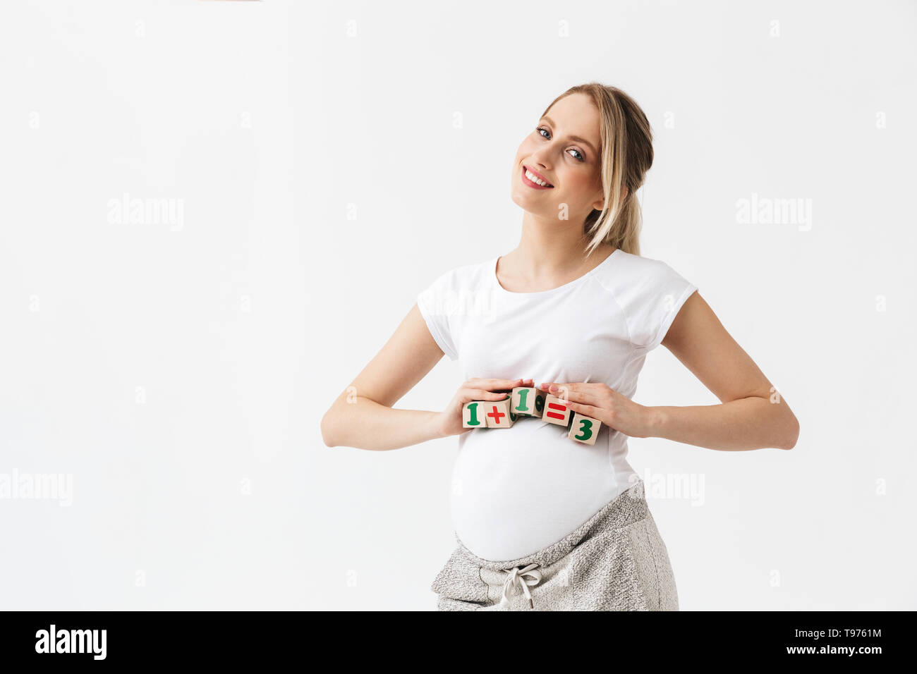 Beautiful young pregnant woman standing isolated over white background ...