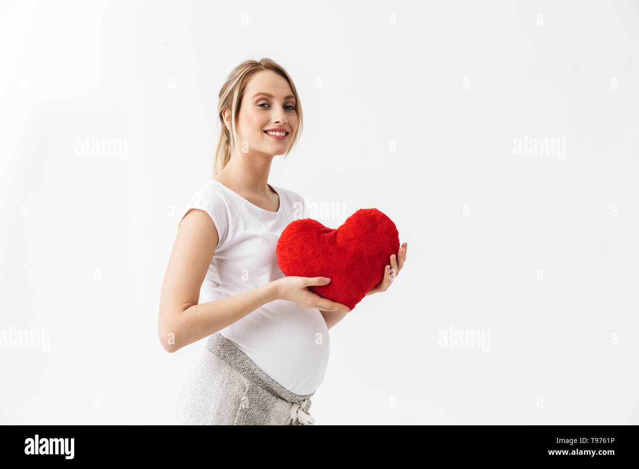 Beautiful young pregnant woman standing isolated over white background ...