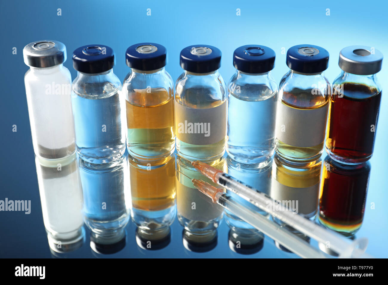 Different ampules with syringe on color background Stock Photo - Alamy