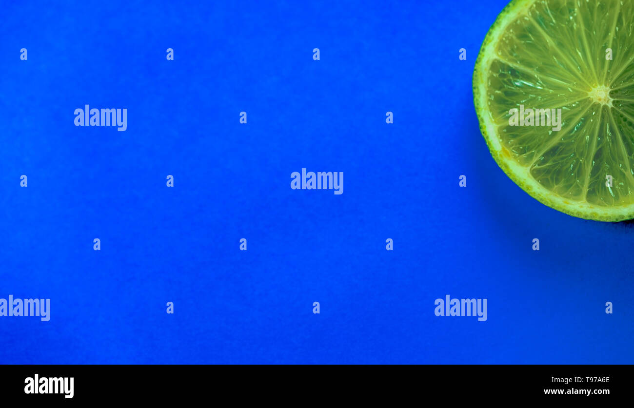 close up view of an isolated slice of lime fruit on a bright blue ...