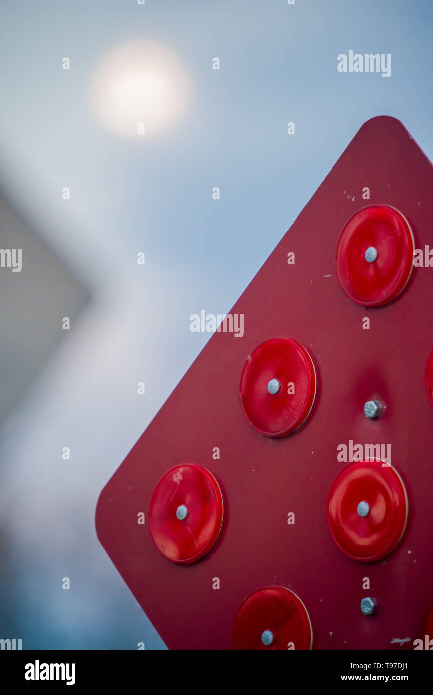 Parts of two diamond shaped red warning signs with red reflectors with ...