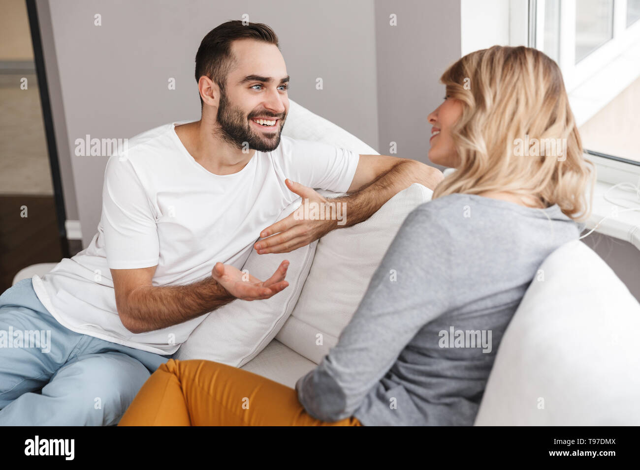 Image of young cute loving couple indoors at home talking with each ...