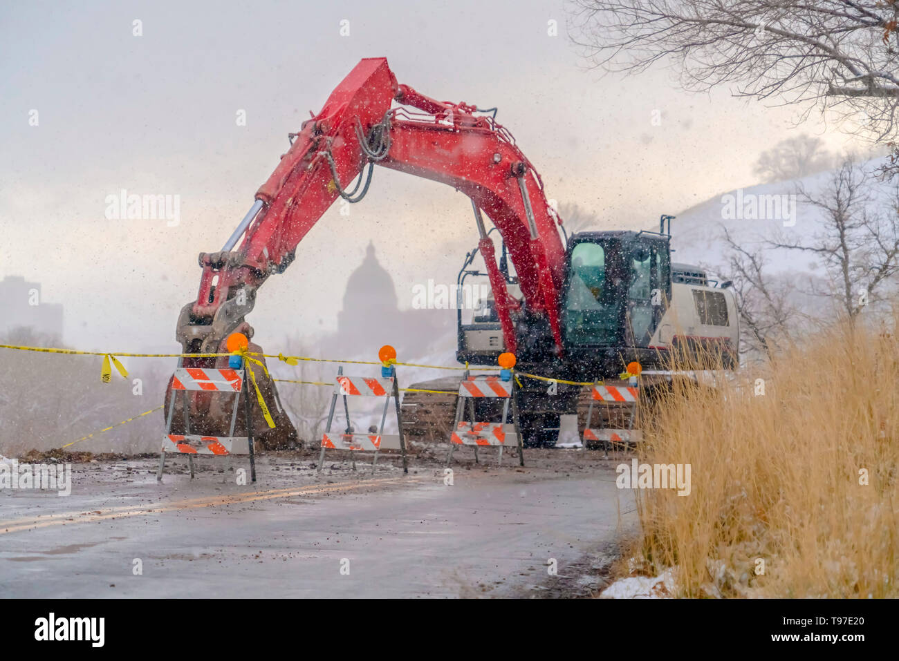 Red excavator and barricades on a snowy mountain road in winter Stock ...
