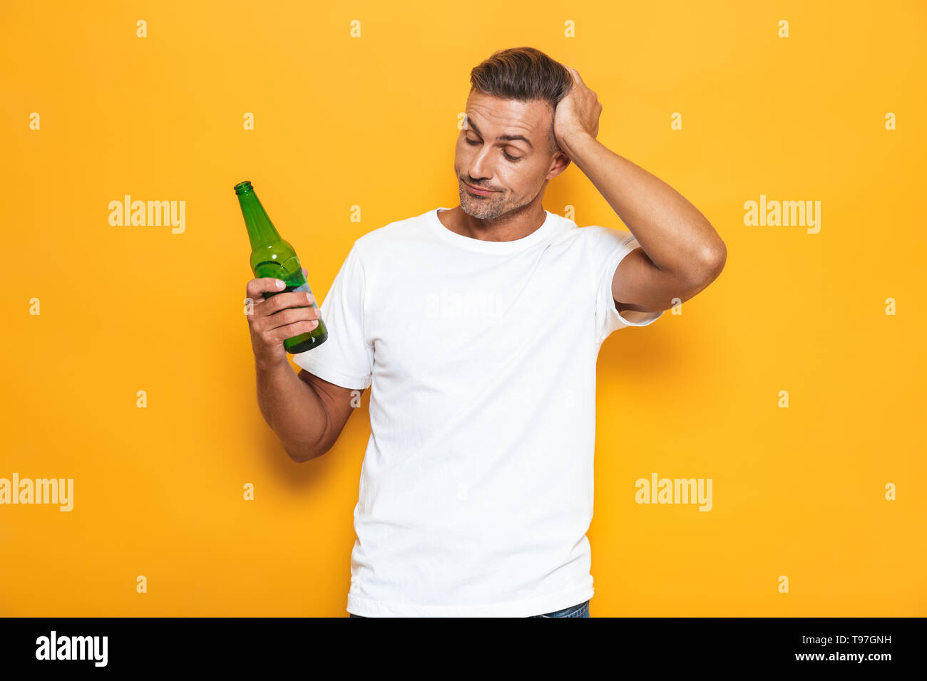 Image of drunk man 30s in white t-shirt holding bottle and drinking ...