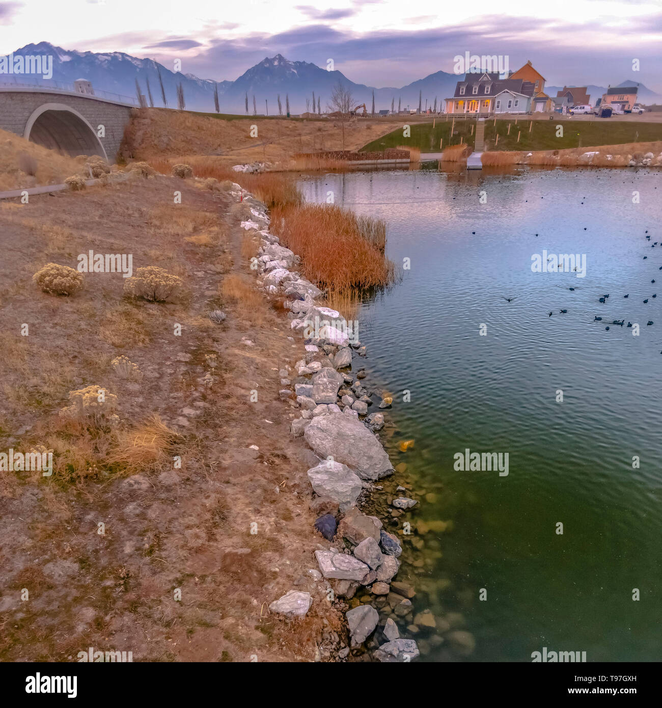 Clear Square Lake with rocks lining the shore and an arched bridge over ...