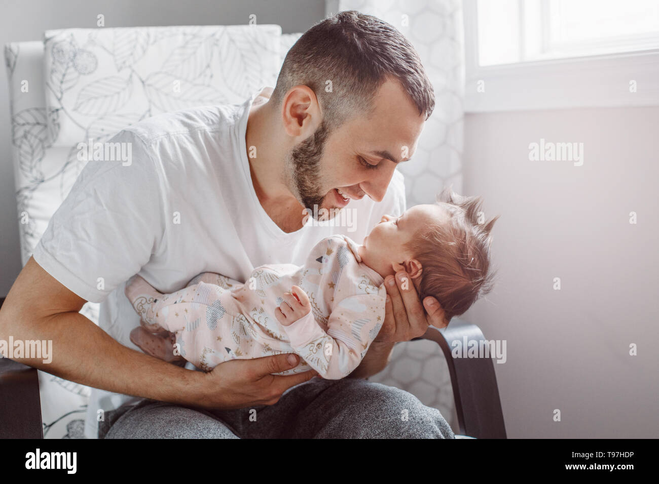 Caucasian father sitting in armchair with newborn baby girl. Parent ...