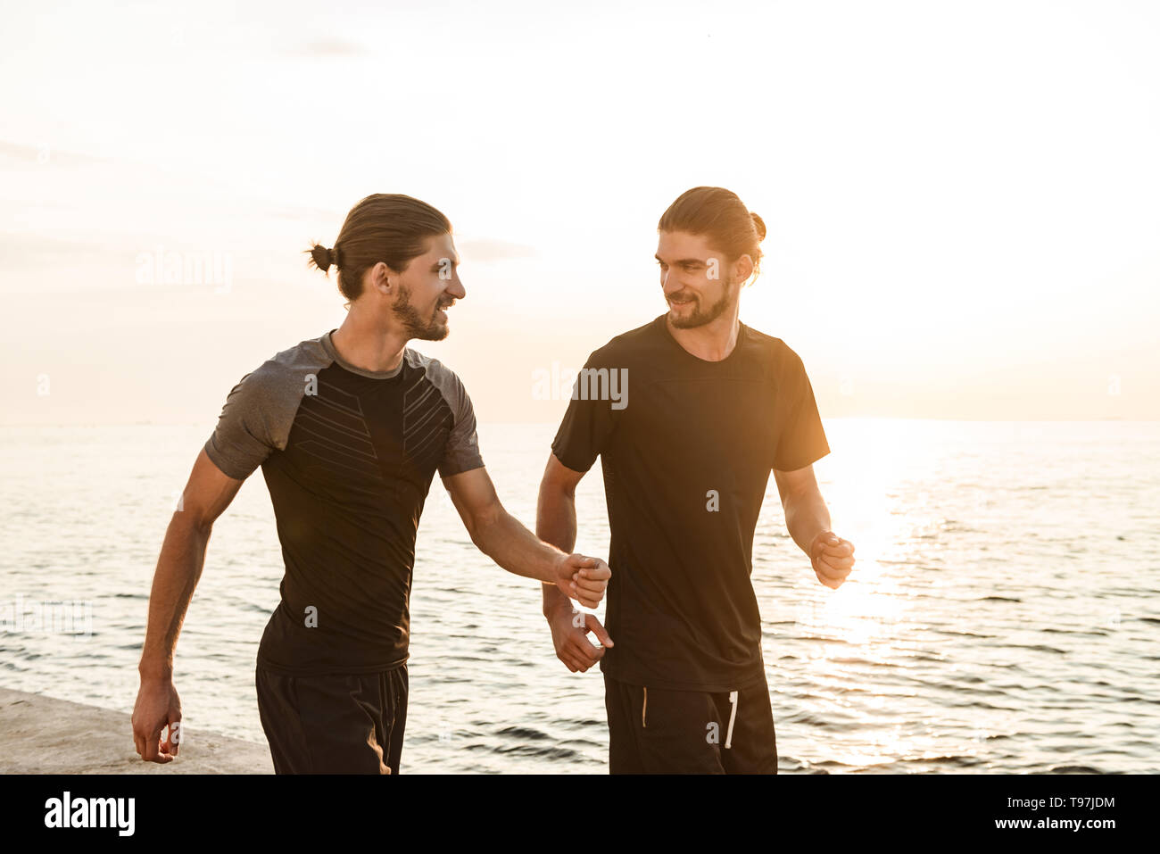 Two twin brothers doing exercises at the beach together, jogging Stock ...