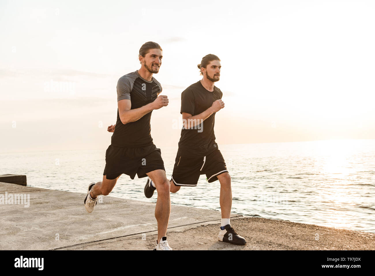 Two twin brothers doing exercises at the beach together, jogging Stock ...