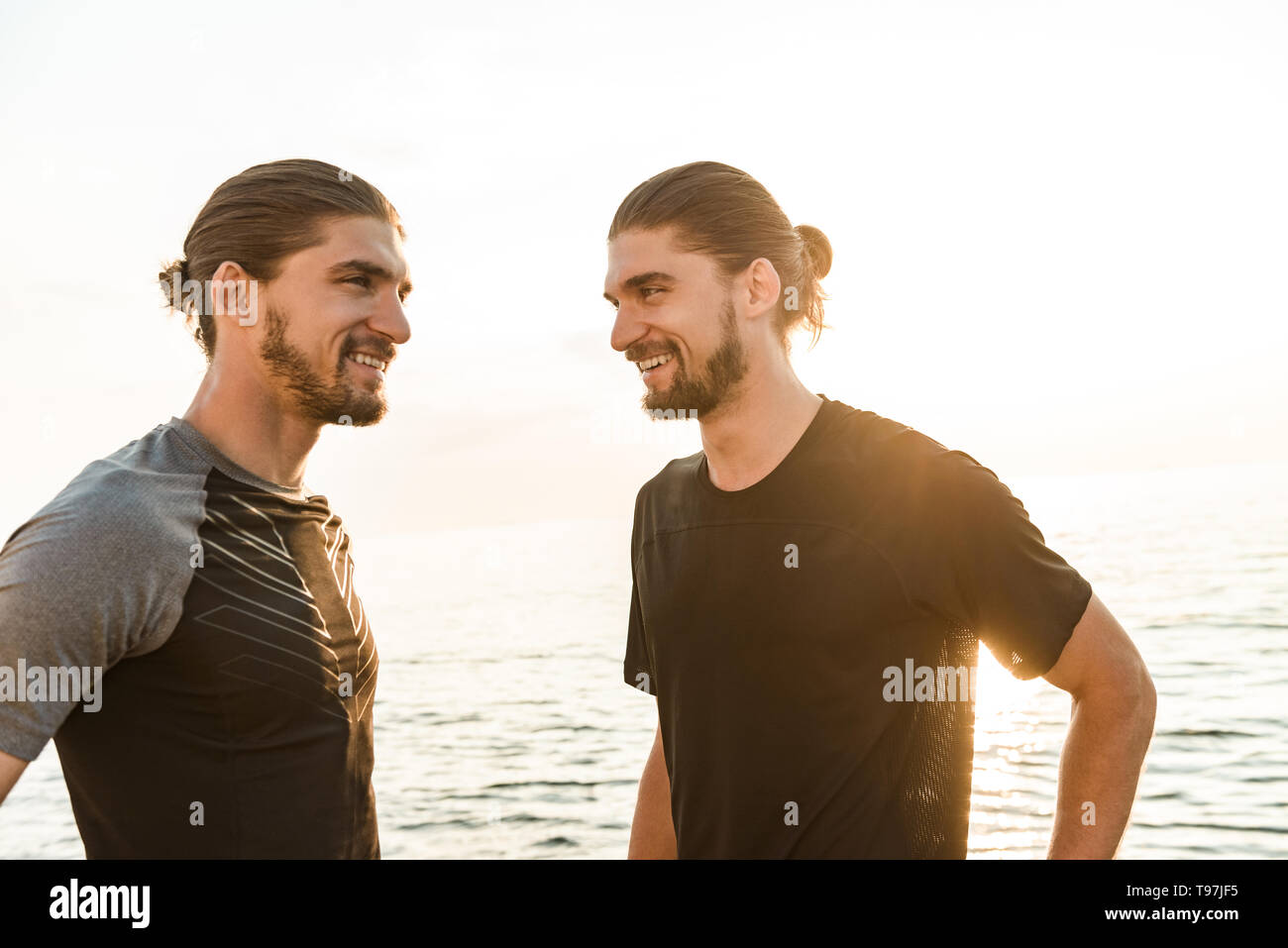Two twin brothers doing exercises at the beach together, talking Stock ...