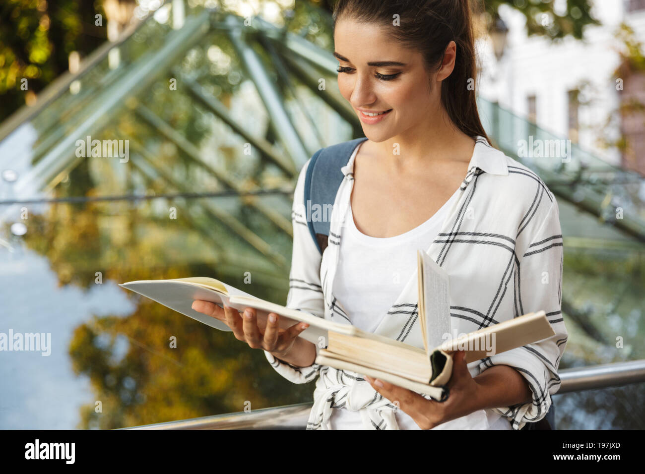 Pretty girl student reading a book while standing at the park Stock ...