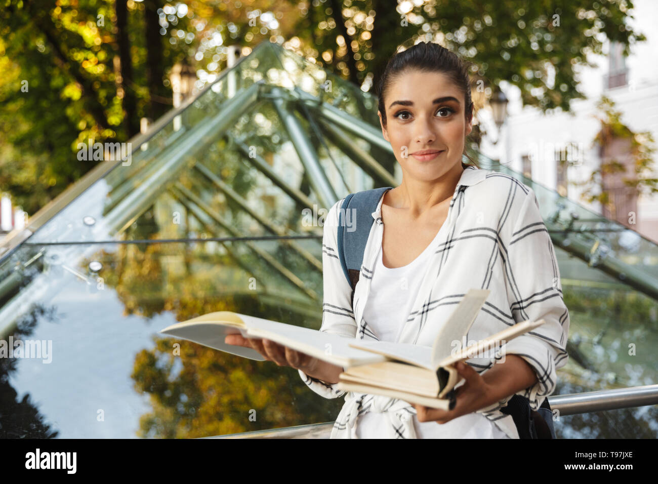 Pretty girl student reading a book while standing at the park Stock ...