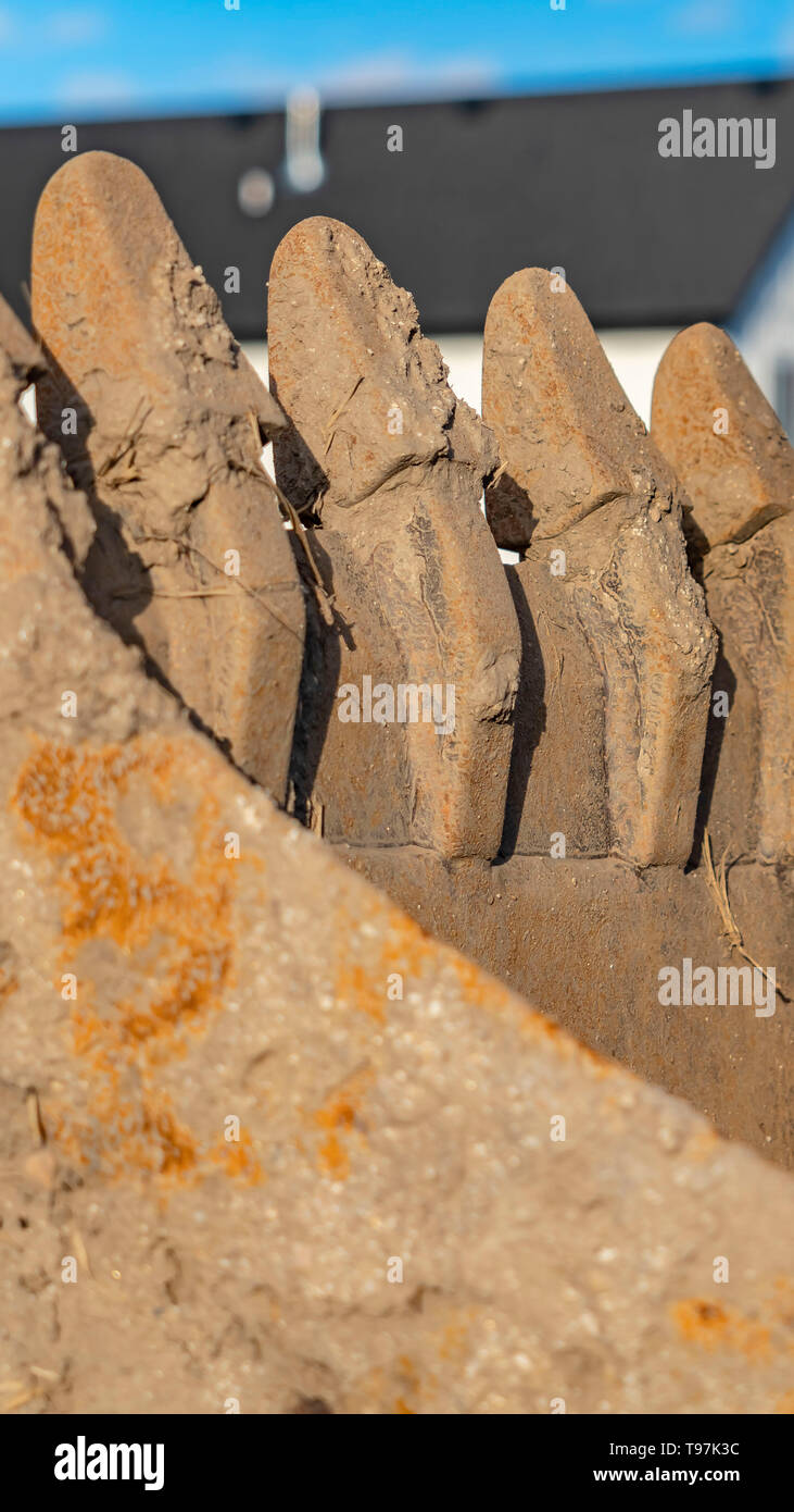 Vertical Dirty and rusty metal bucket teeth of an excavator viewed on a ...