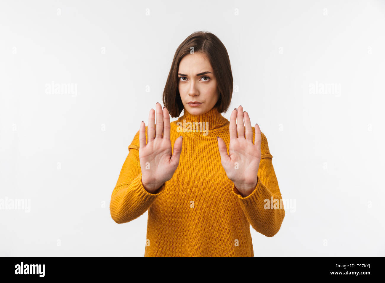 Serious young girl standing isolated over white background, showing ...