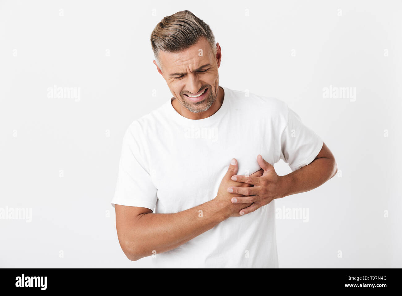 Image of suffering man 30s with bristle wearing casual t-shirt touching ...