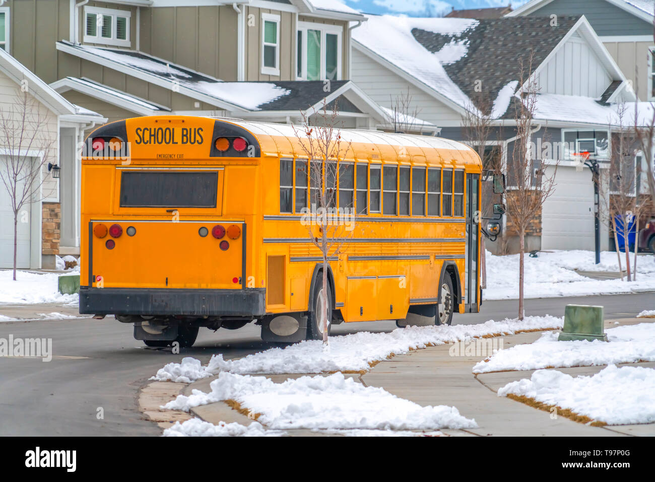 Rear view of a yellow school bus running on a road with fresh snow in ...
