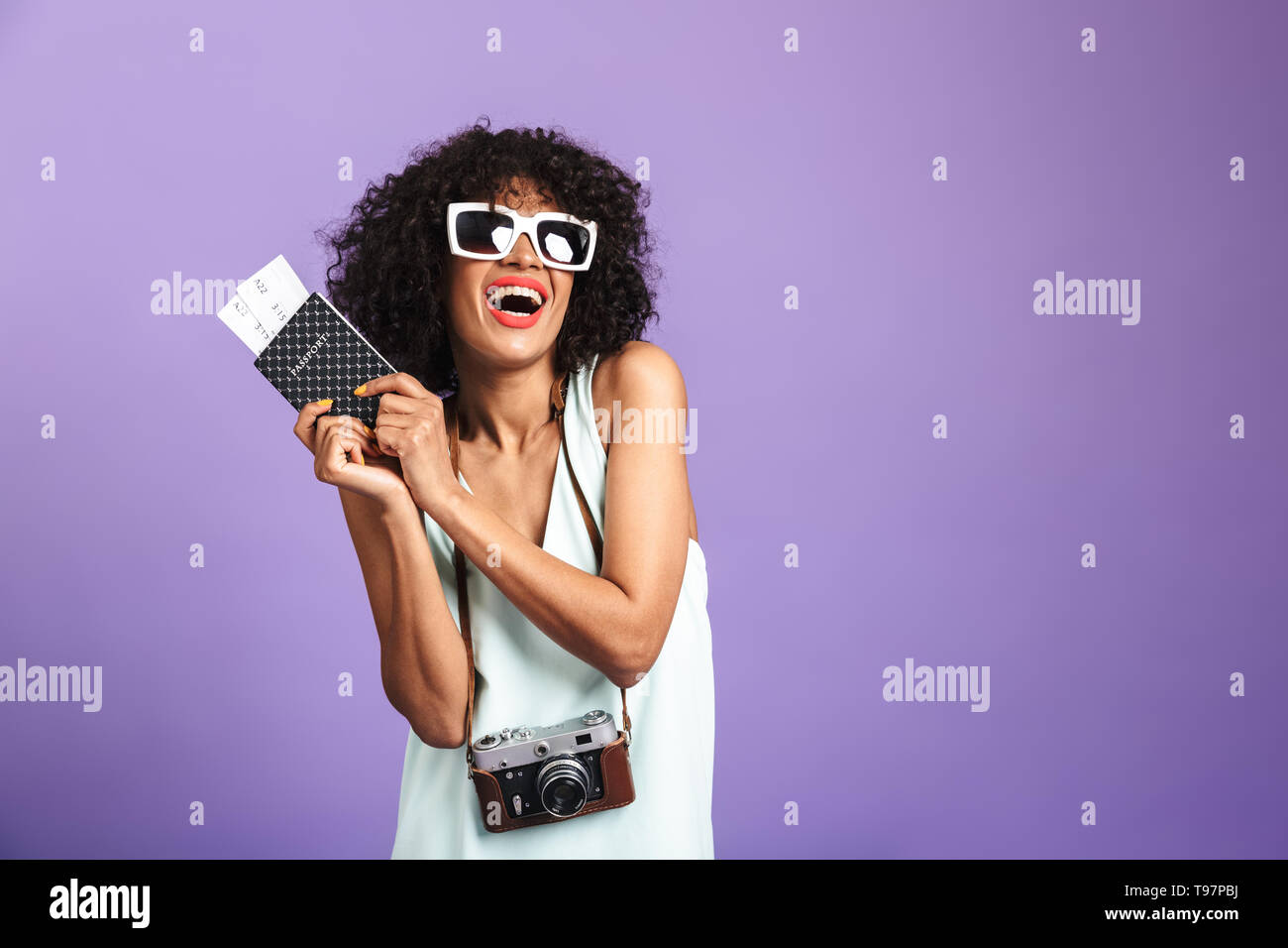 Happy pretty african woman in sunglasses holding passport with tickets ...