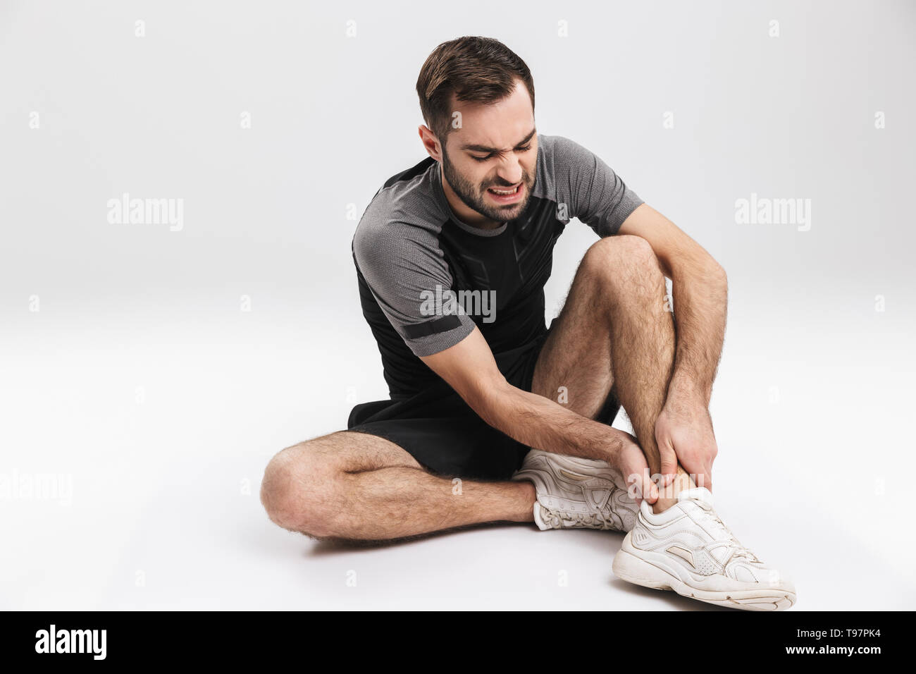 Image of a sad young sports fitness man sitting on floor isolate over ...