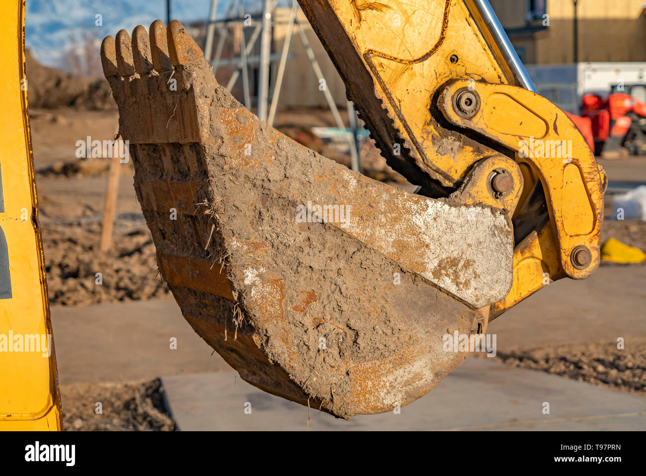 The bucket of a yellow excavator viewed at a construction site on a ...