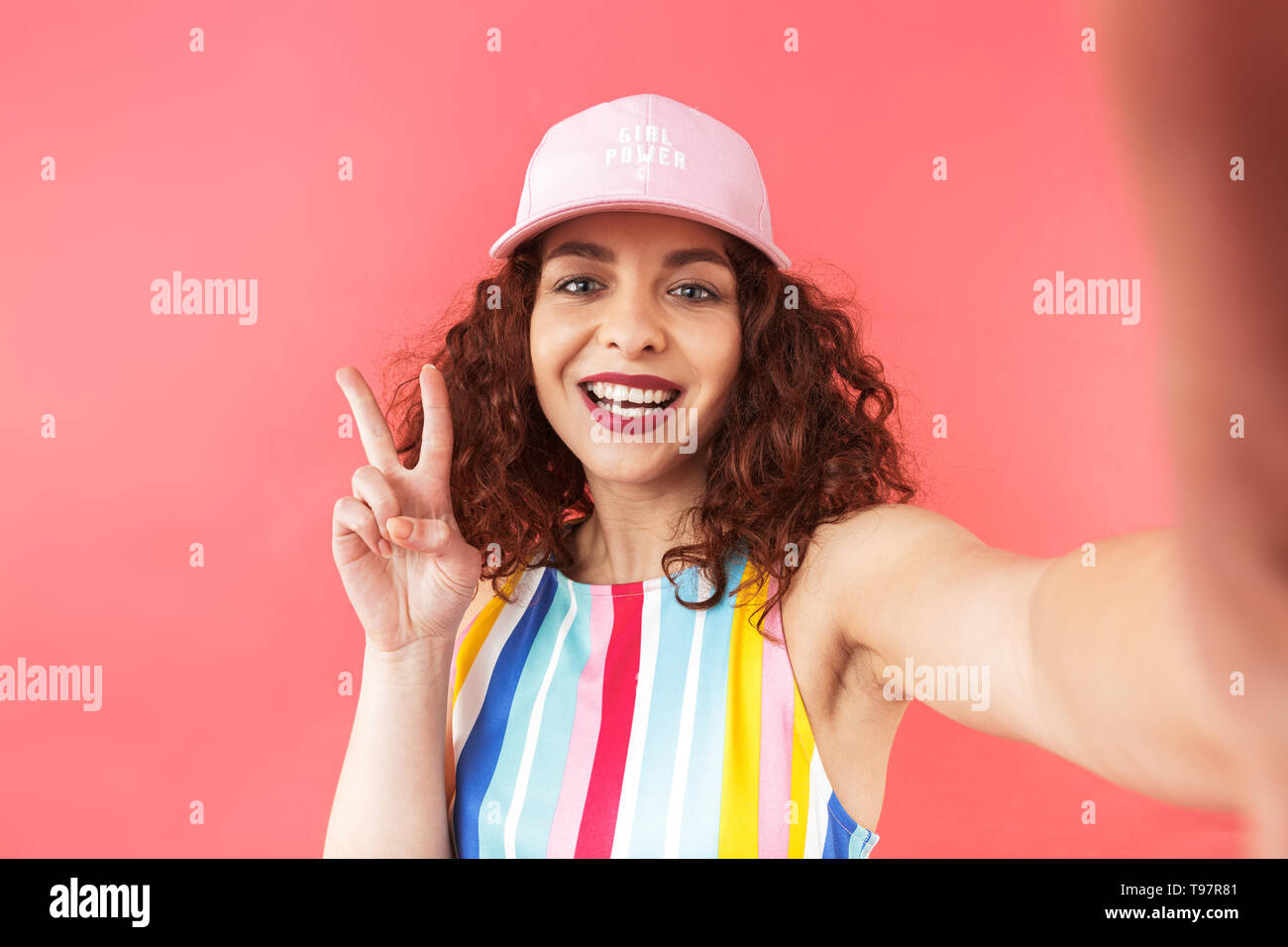 Portrait of a cheerful young woman wearing cap standing isolated over ...