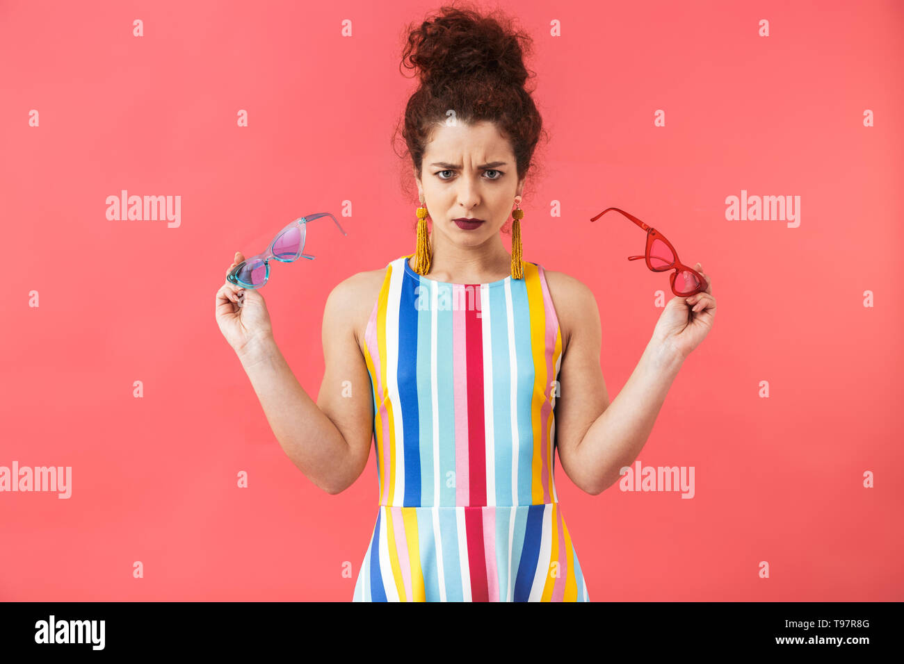 Portrait of a confused young woman wearing dress standing isolated over ...