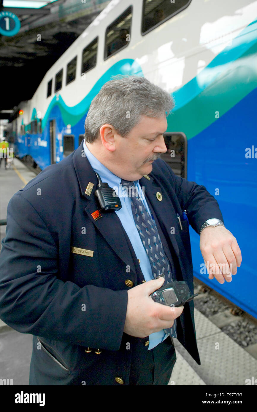 A passenger train conductor checks his watch before announcing the on ...