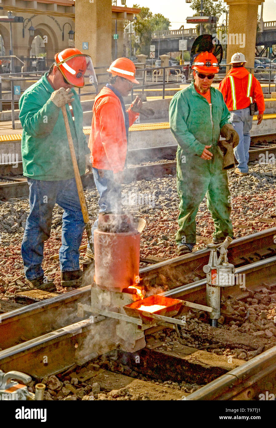 Wearing a hard hat and facial safety mask, a train maintenance worker ...