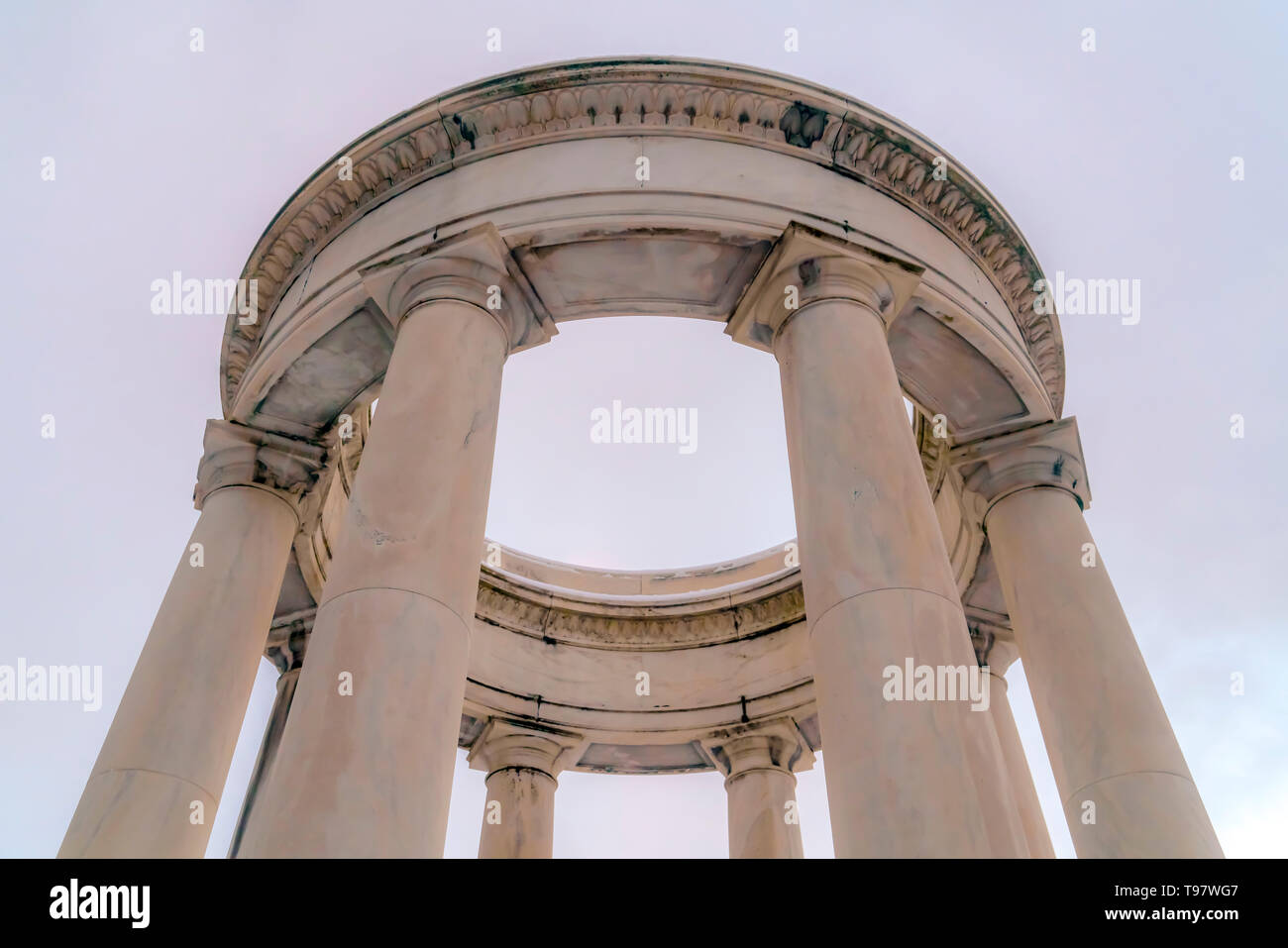 Looking up at a white circular structure supported by smooth columns ...