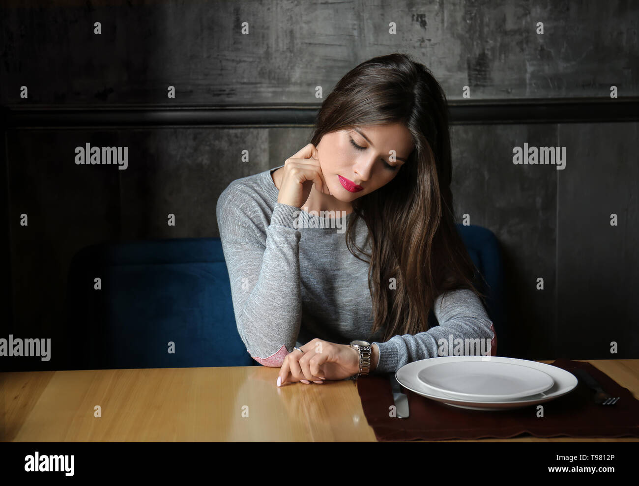 Young woman looking at watch while waiting for her boyfriend in ...