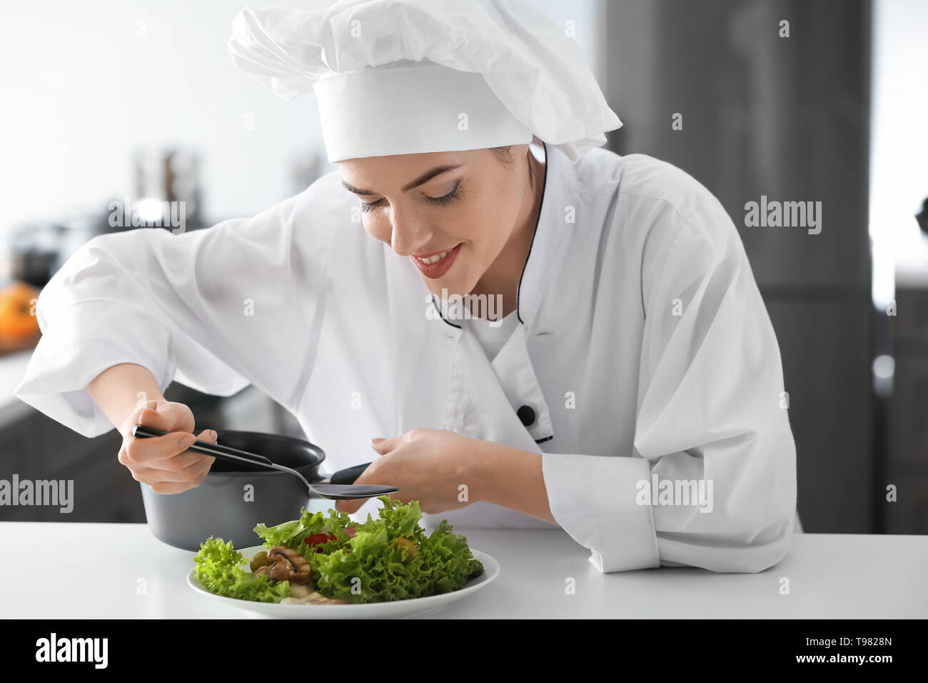 Young female chef dressing tasty salad in kitchen Stock Photo - Alamy