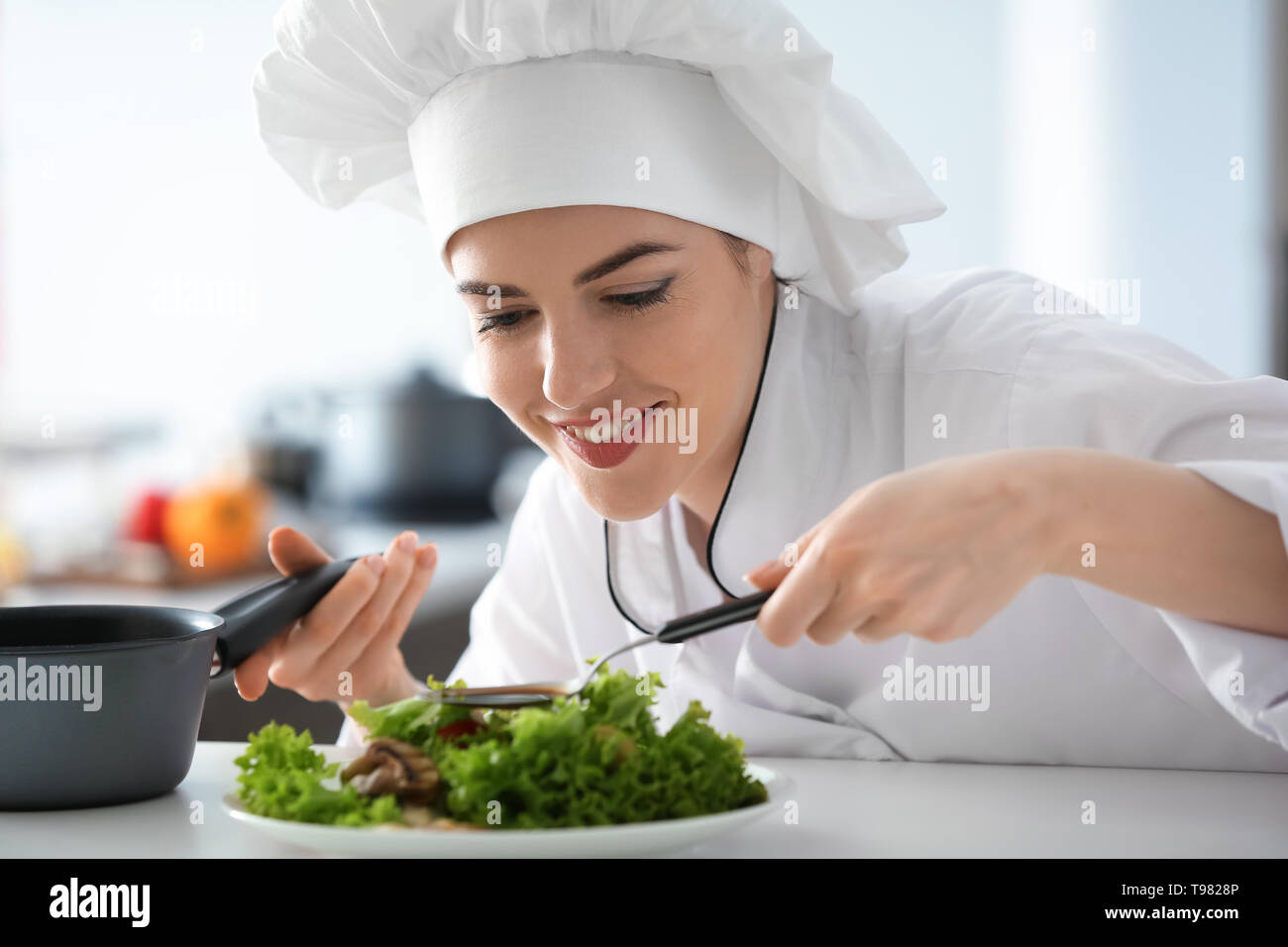 Young female chef dressing tasty salad in kitchen Stock Photo - Alamy