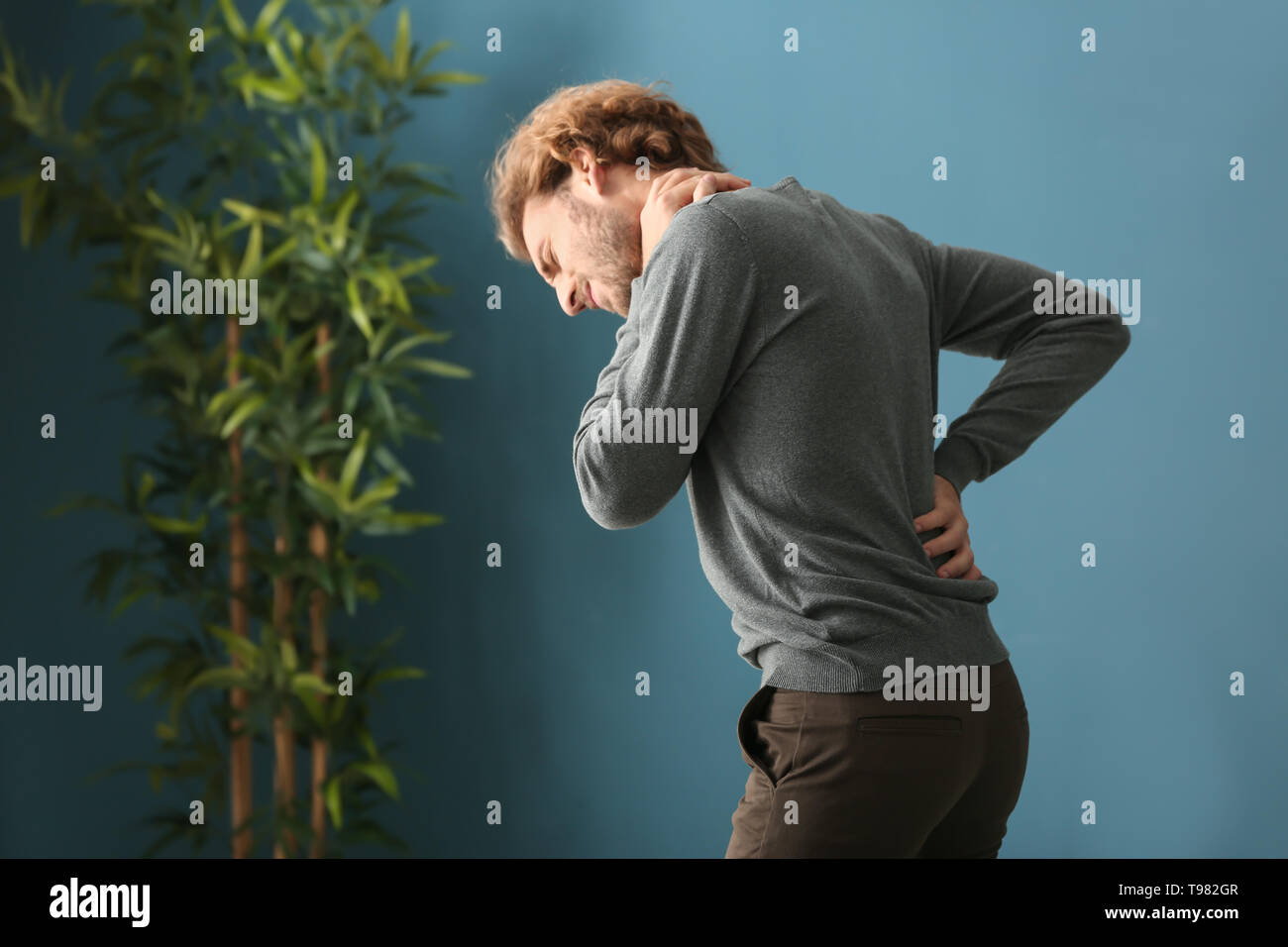 Young man suffering from back pain at home Stock Photo - Alamy