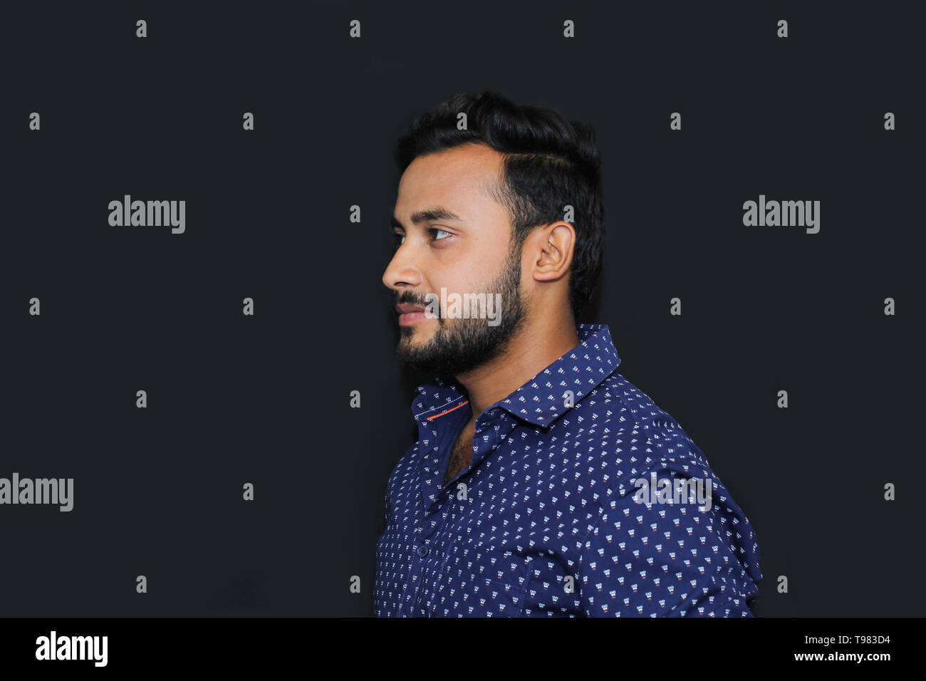 portrait of a young man model side view with black isolated background ...