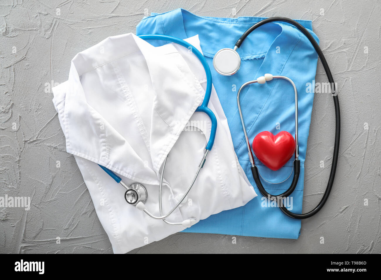 Doctor's uniform with stethoscope and red heart on grey table. Health ...