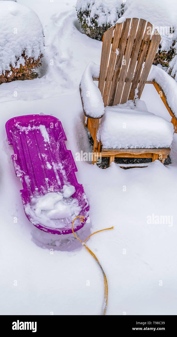 Vertical Wooden chairs and purple sled against powdery white snow in ...