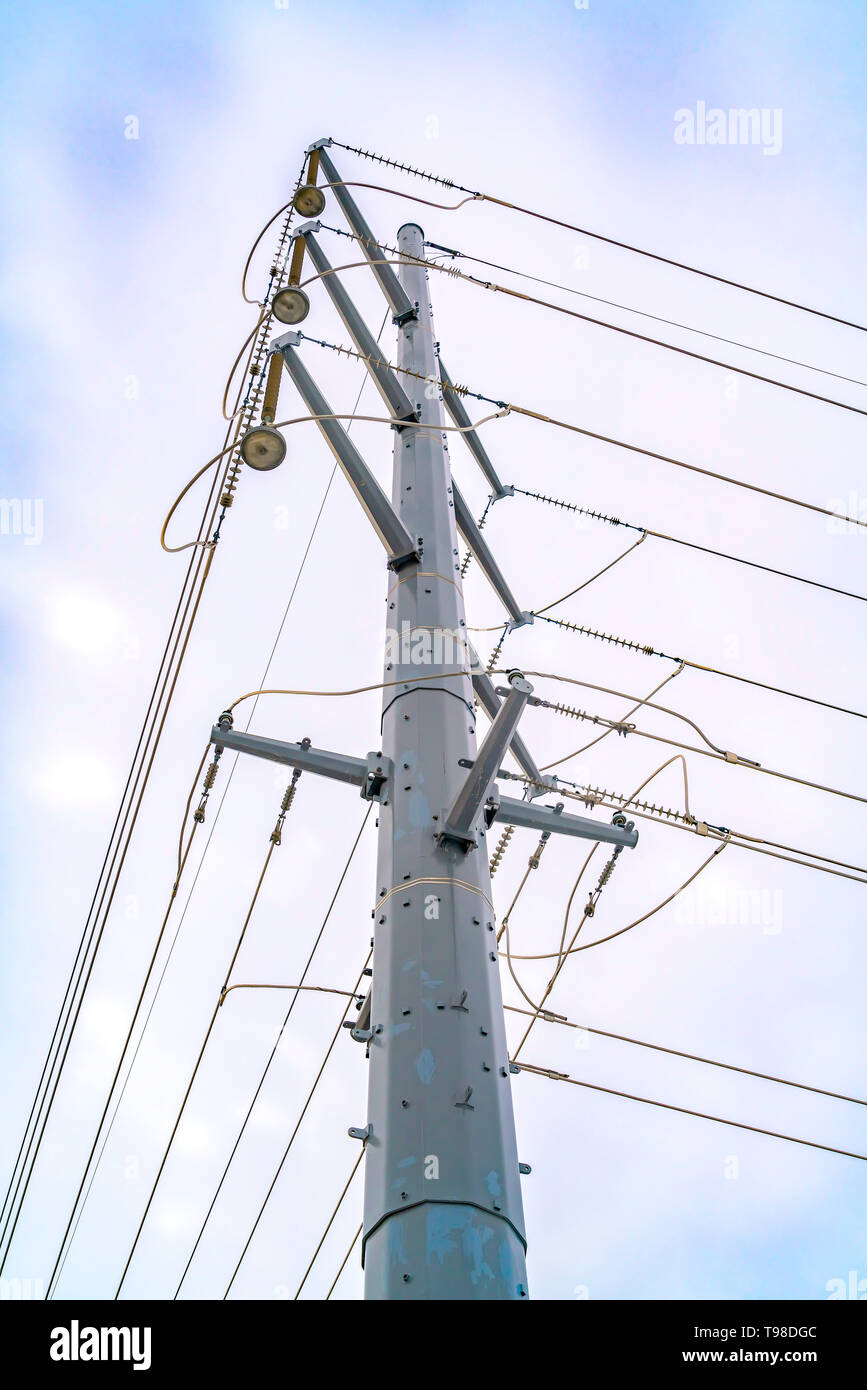 Looking up at a towering metal post supporting overhead power lines ...