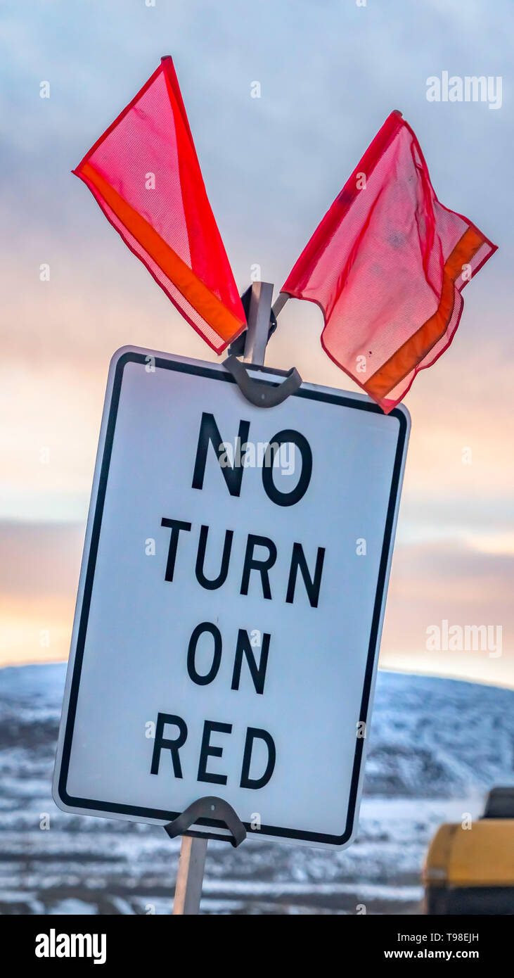 Clear Vertical Close up of a No Turn On Red sign with red flags on top ...
