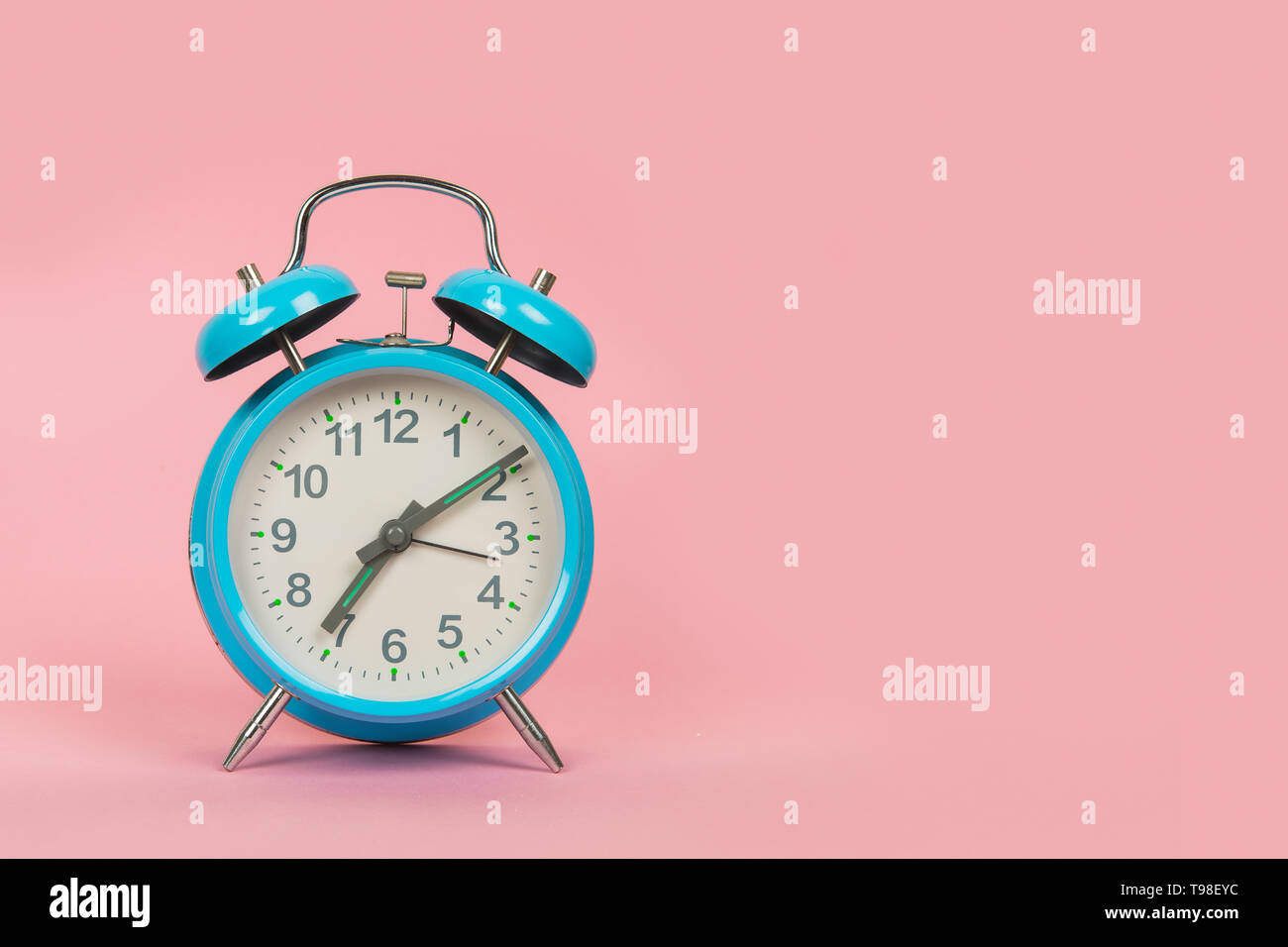 Blue vintage alarm clock on a pink background with space for copy with ...