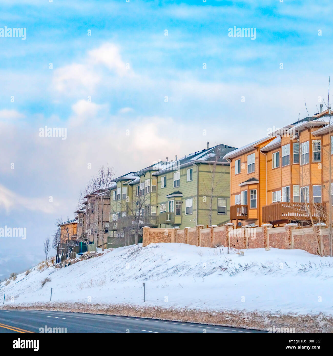 Square Scenic view of colorful houses on a snowy slope beside a paved ...