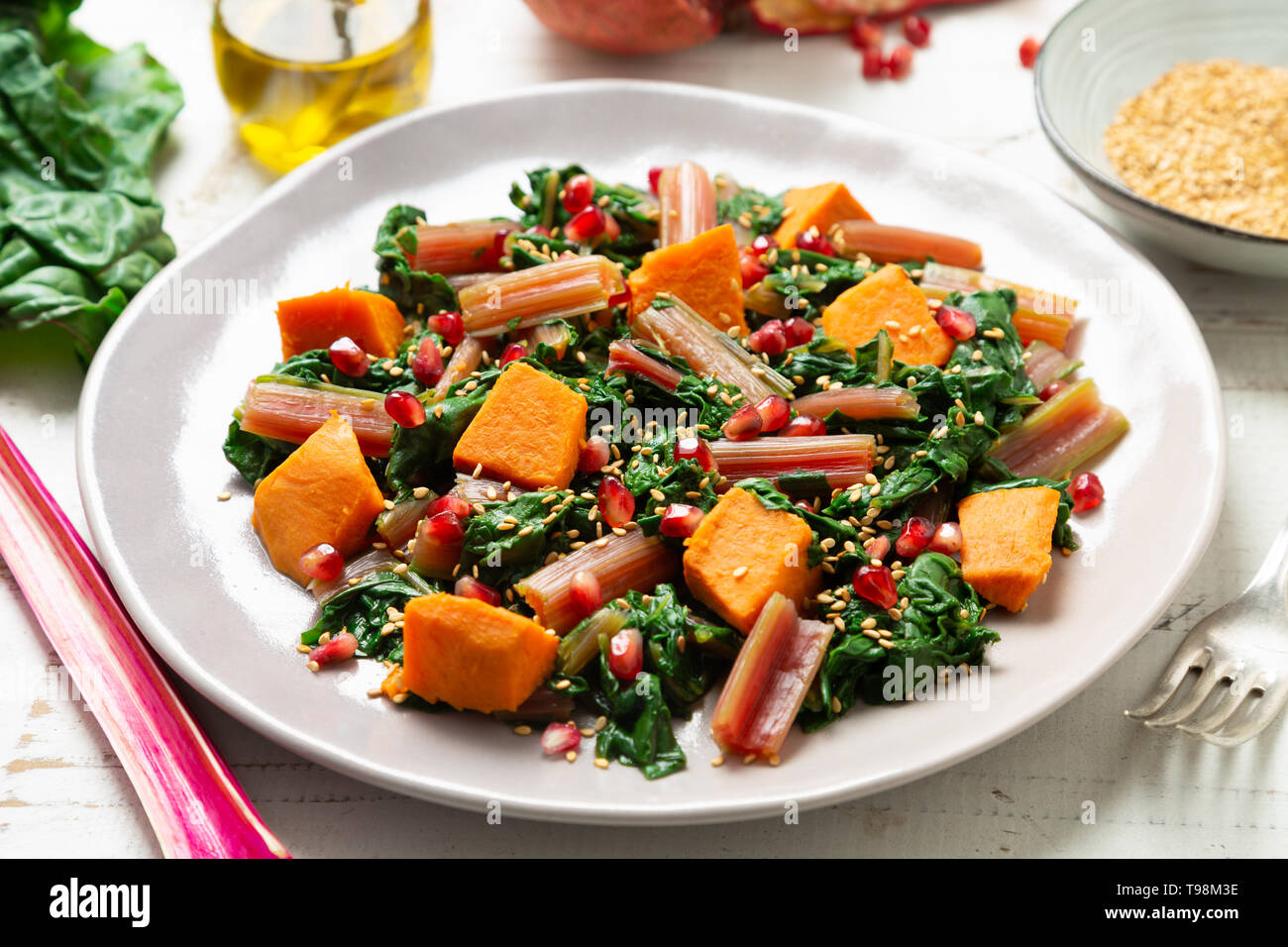 Boiled swiss chard with sweet potato, pomegranate and sesame seeds on a ...